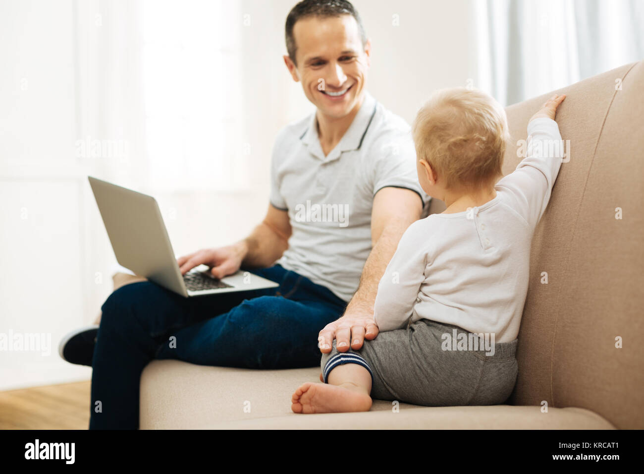 Peaceful cheerful father looking at his child and smiling happily Stock ...