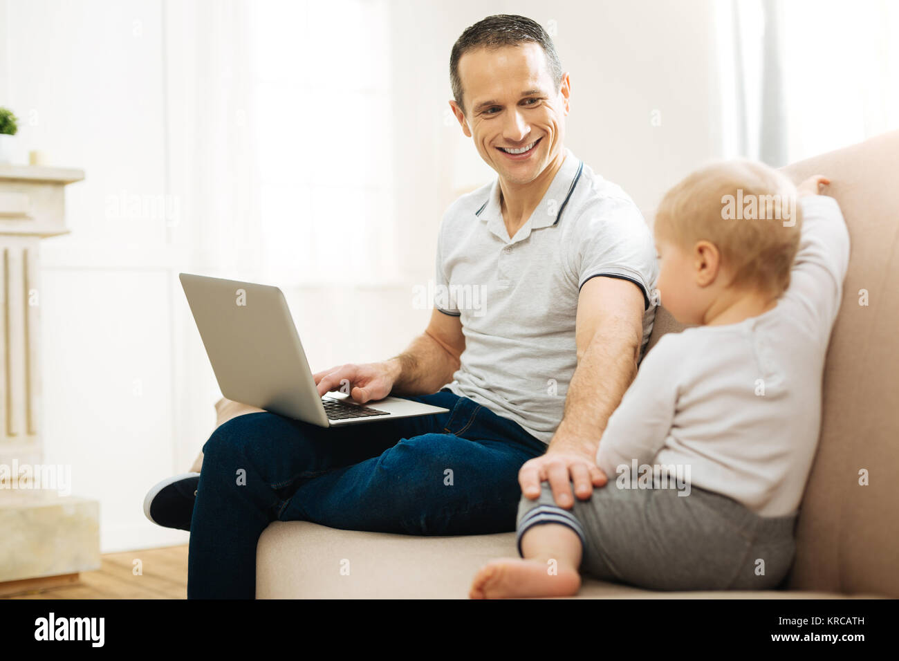 Experienced kind father looking at his adorable child and smiling ...