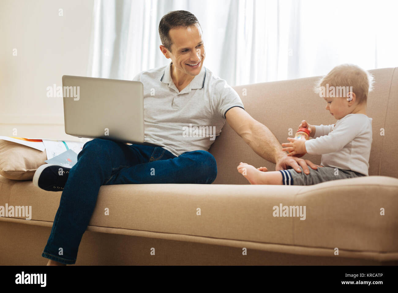 Positive young father looking proud of the developing child Stock Photo ...