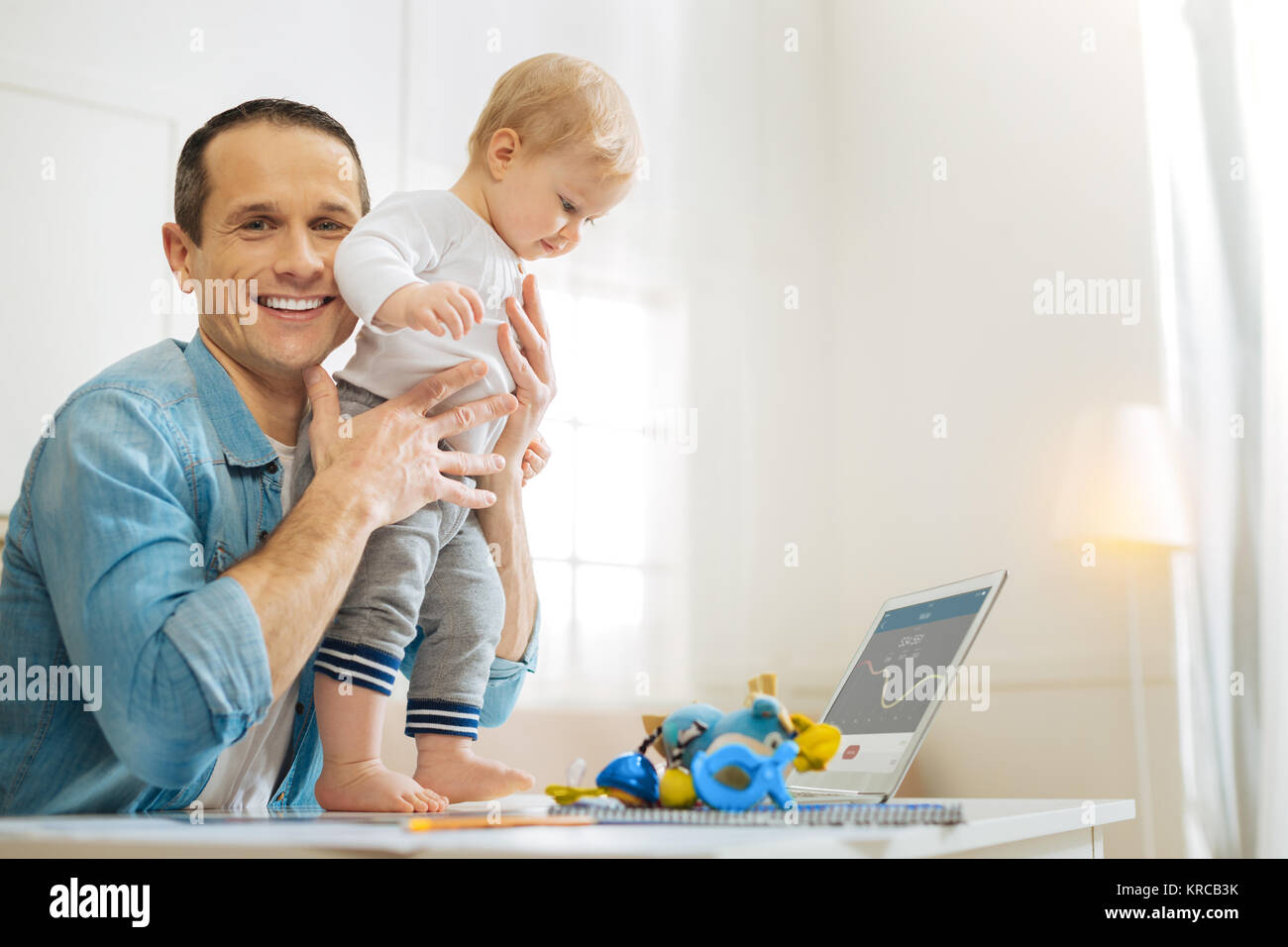 Happy parent helping his amazing baby to stand on the table Stock Photo ...