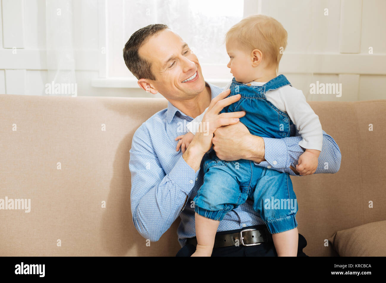 Attentive baby looking at his father while sitting with him Stock Photo ...