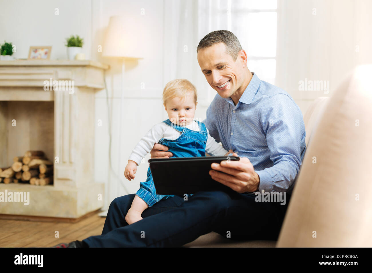 Kind attentive father smiling while showing a tablet to his child Stock ...