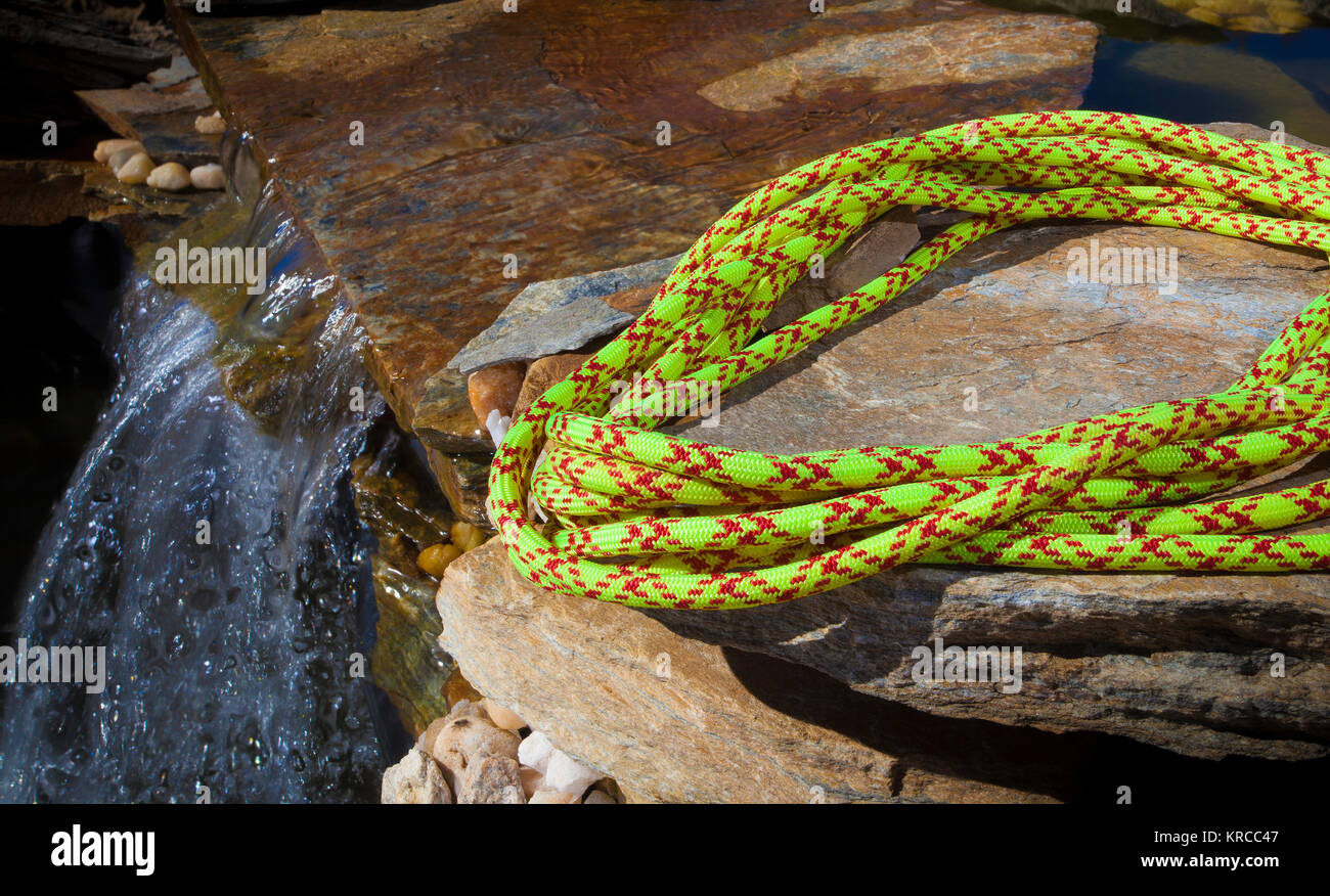 Bright yellow climbing rope next to a smal stream and waterfall Stock ...