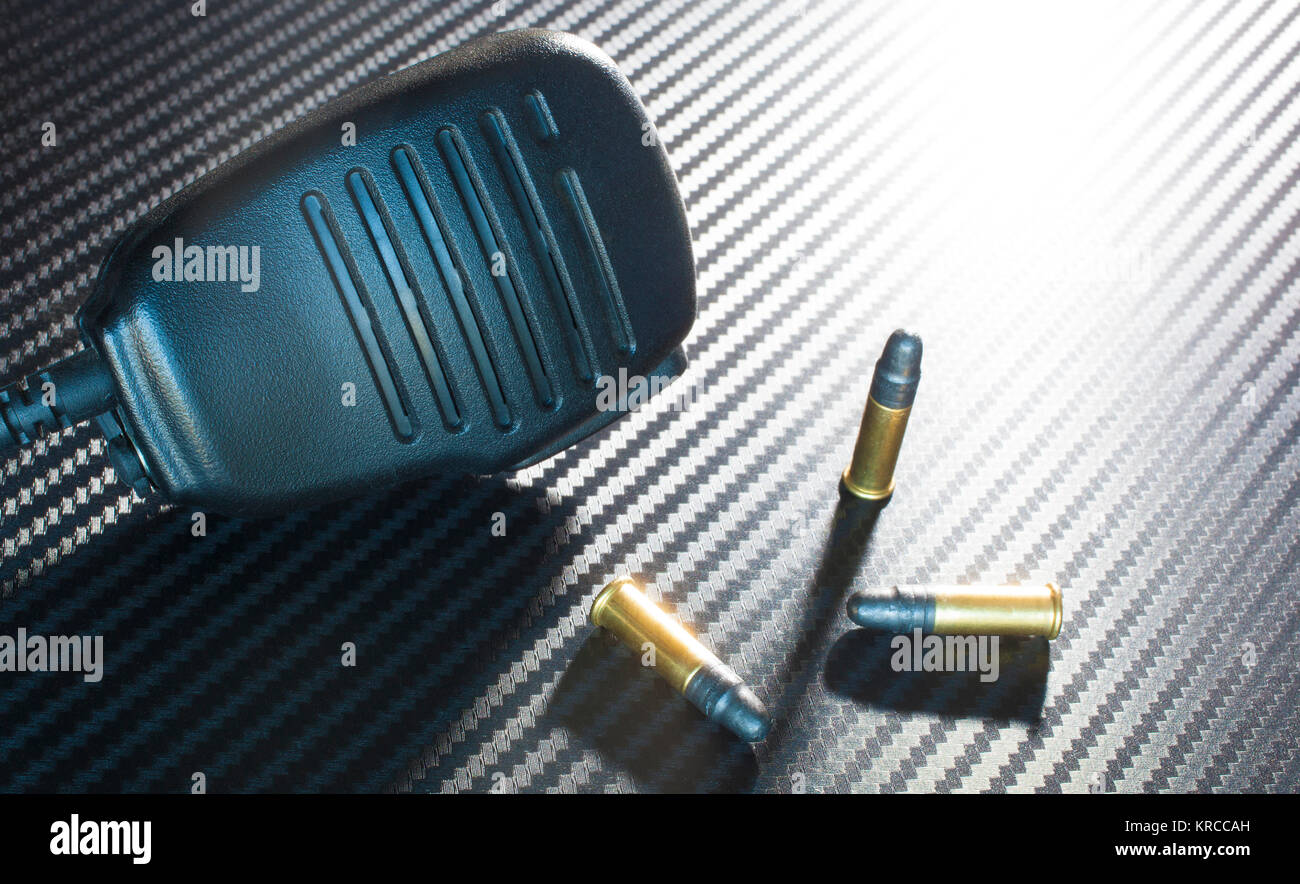 Police microphone with three rim fire cartridges on a dark background ...