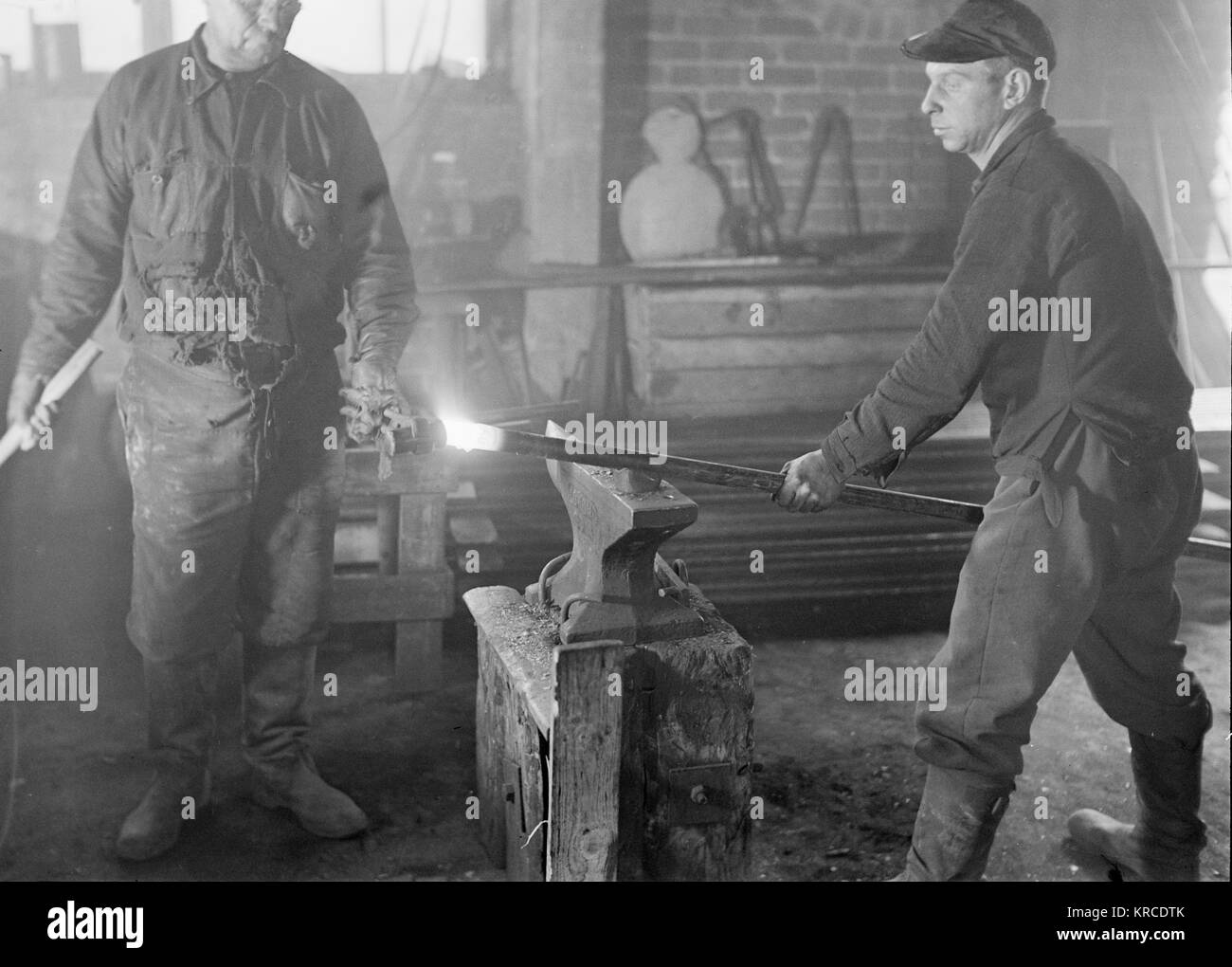 Two workers forging a metal rod in factory workshop, Finland 1950s ...