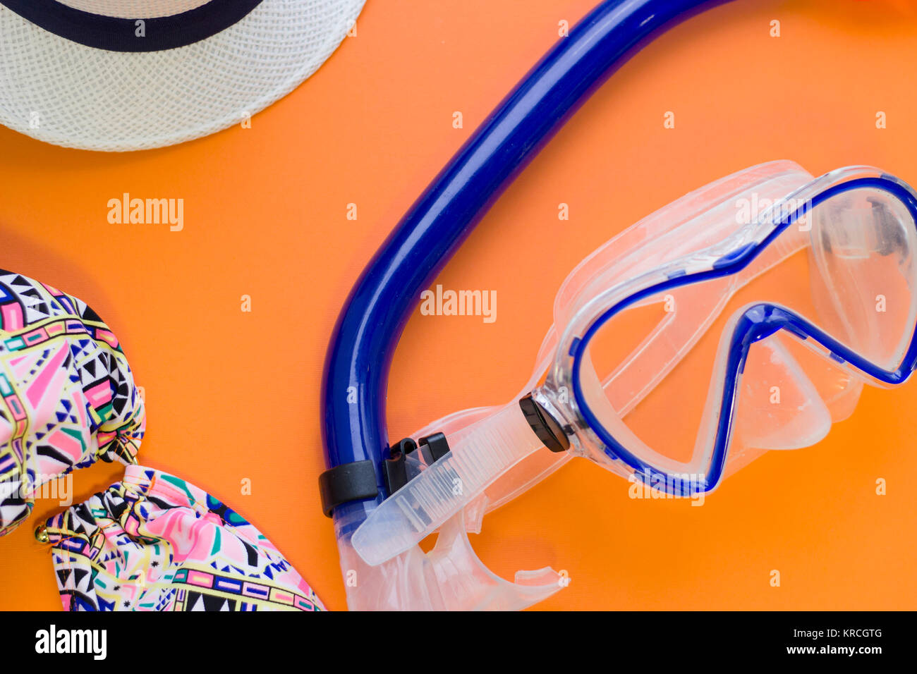 Happy beach vacation. Diving mask and a swim suit on a bright orange ...