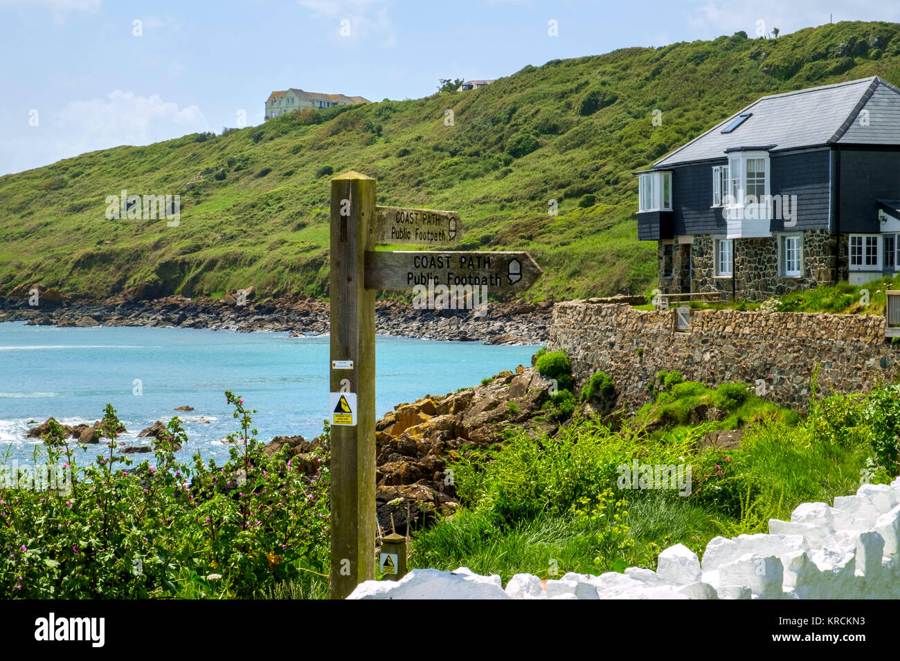 Coast path direction sign post by a clifftop cottage with stunning sea ...