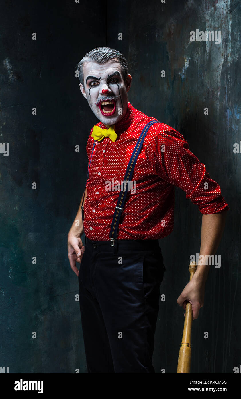 The scary clown and baseball-bat on dack background. Halloween concept ...