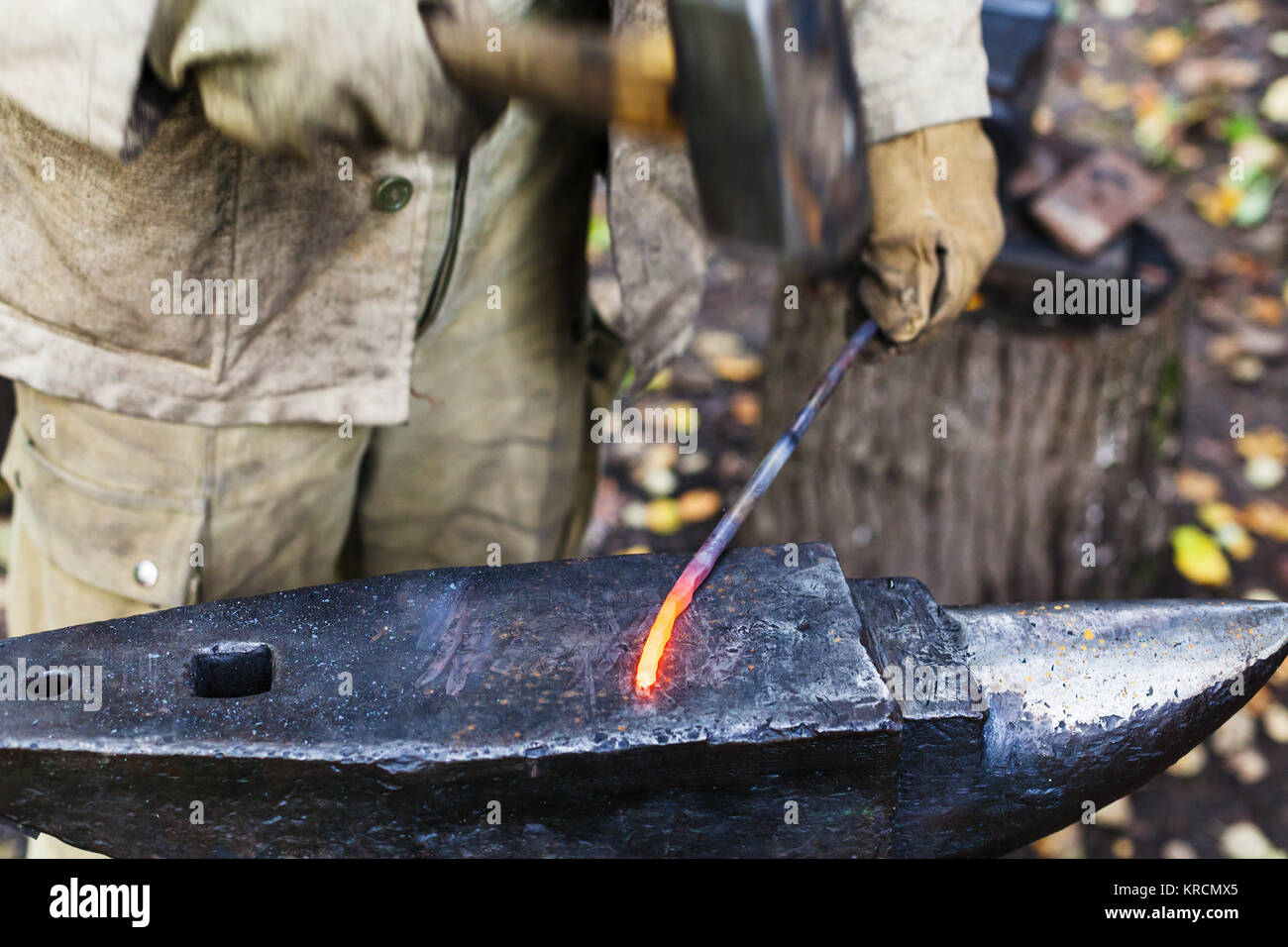 Blacksmith hammering red hot iron rod on anvil Stock Photo - Alamy