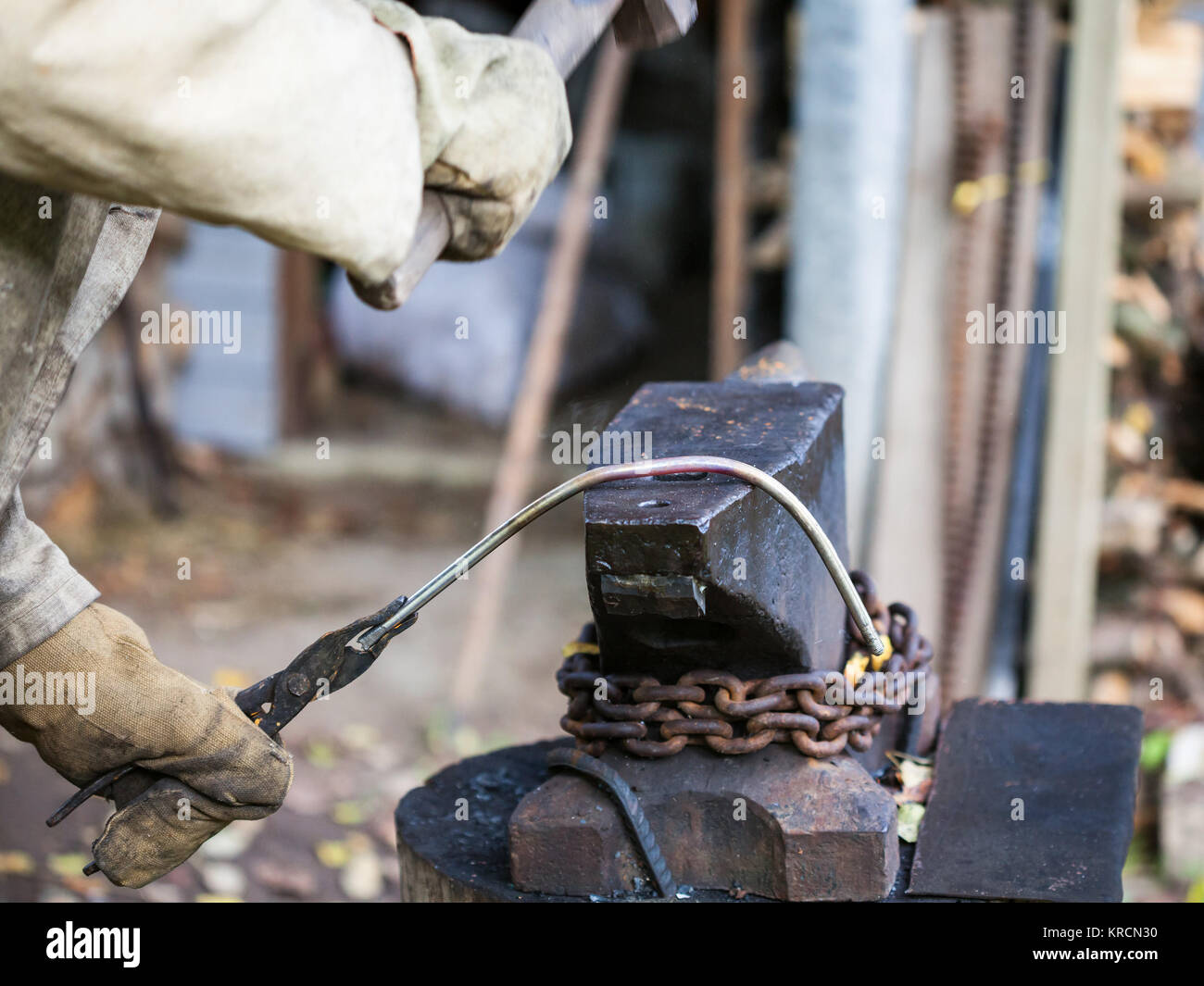 blacksmith forges iron rod on an anvil Stock Photo - Alamy