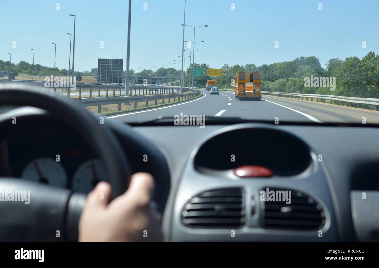 Man driving a car on a highway with other vehicles and direction signs ...