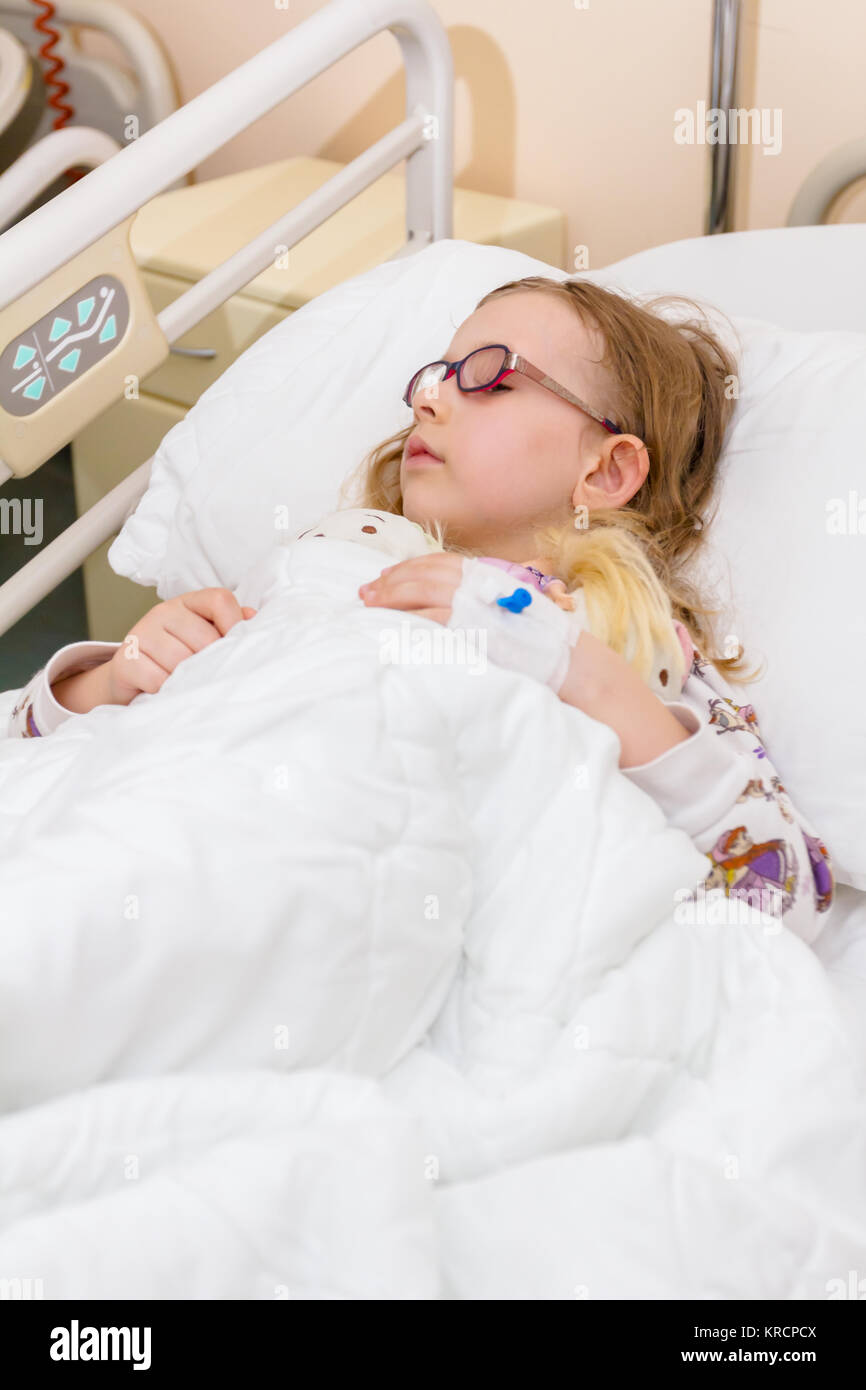 Little girl is resting in a hospital bed with her teddy bear, clinic ...