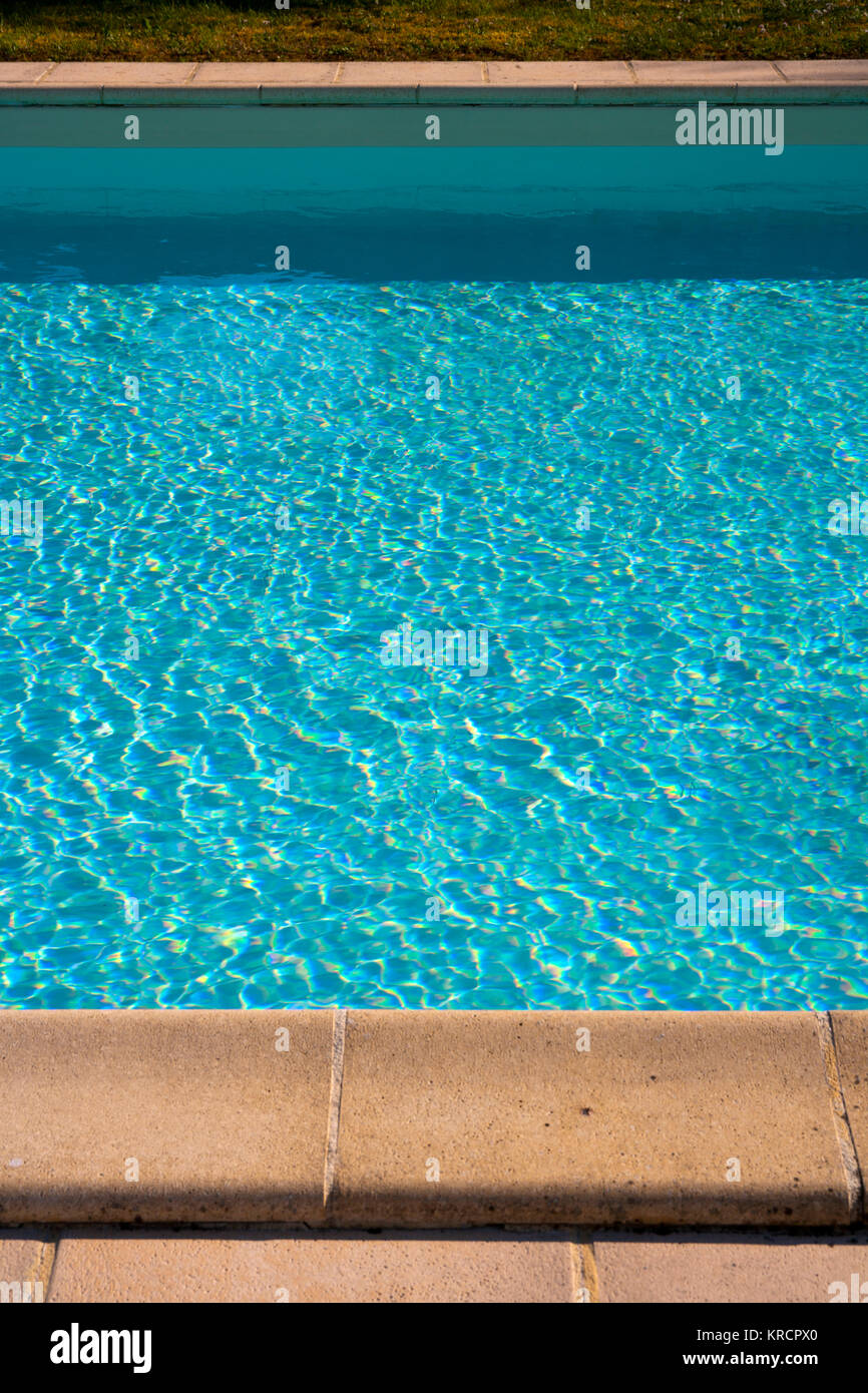 Stone edging detail beside a blue swimming pool sunshine surface ...