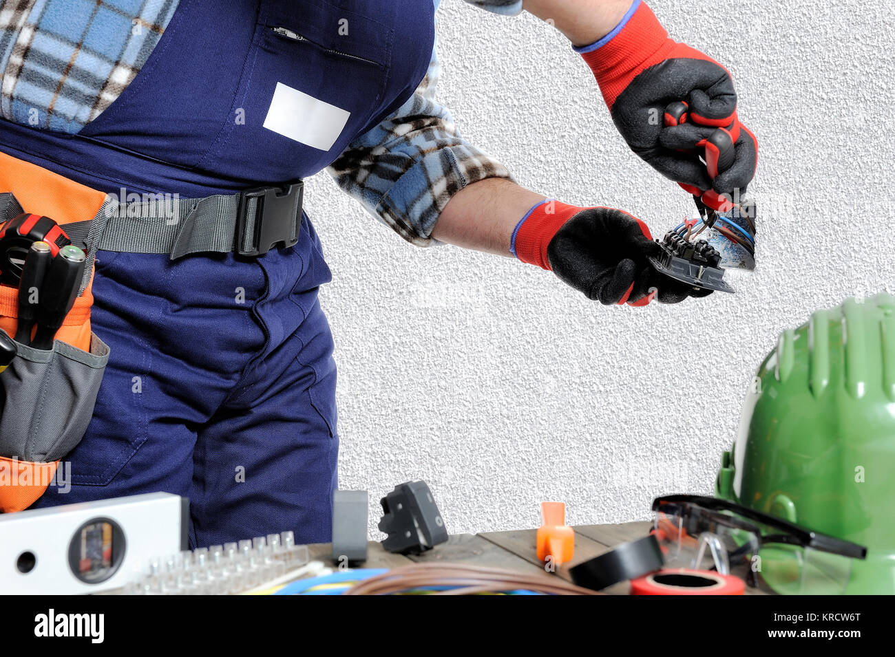 Electrician with hands protected by gloves and insulated tools works ...