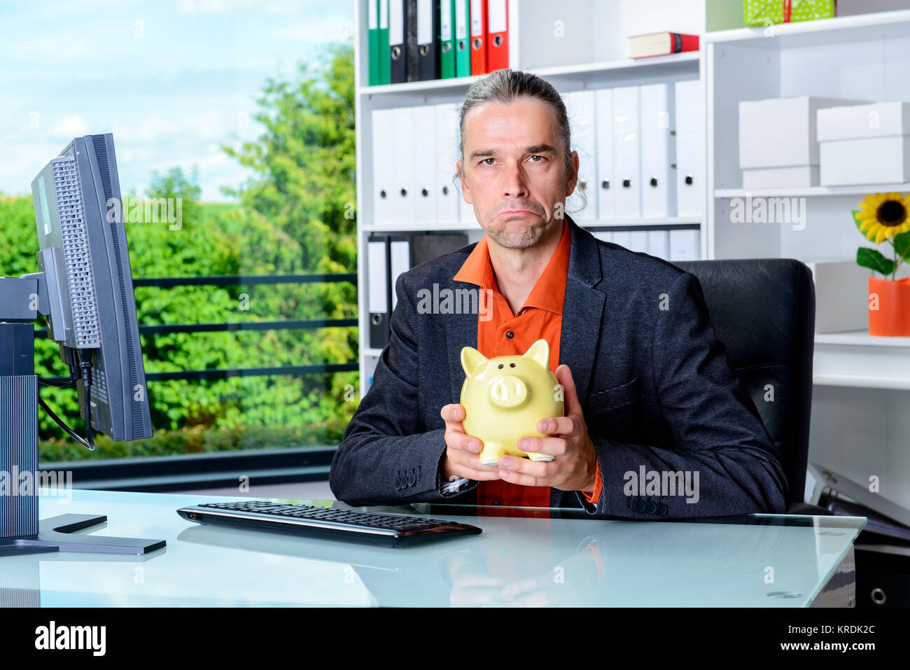 young angry business man at his desk with piggy bank Stock Photo - Alamy