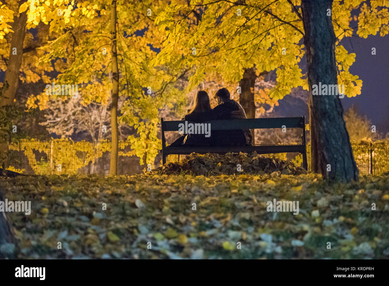 Couple on a bench in an autumn evening Stock Photo - Alamy