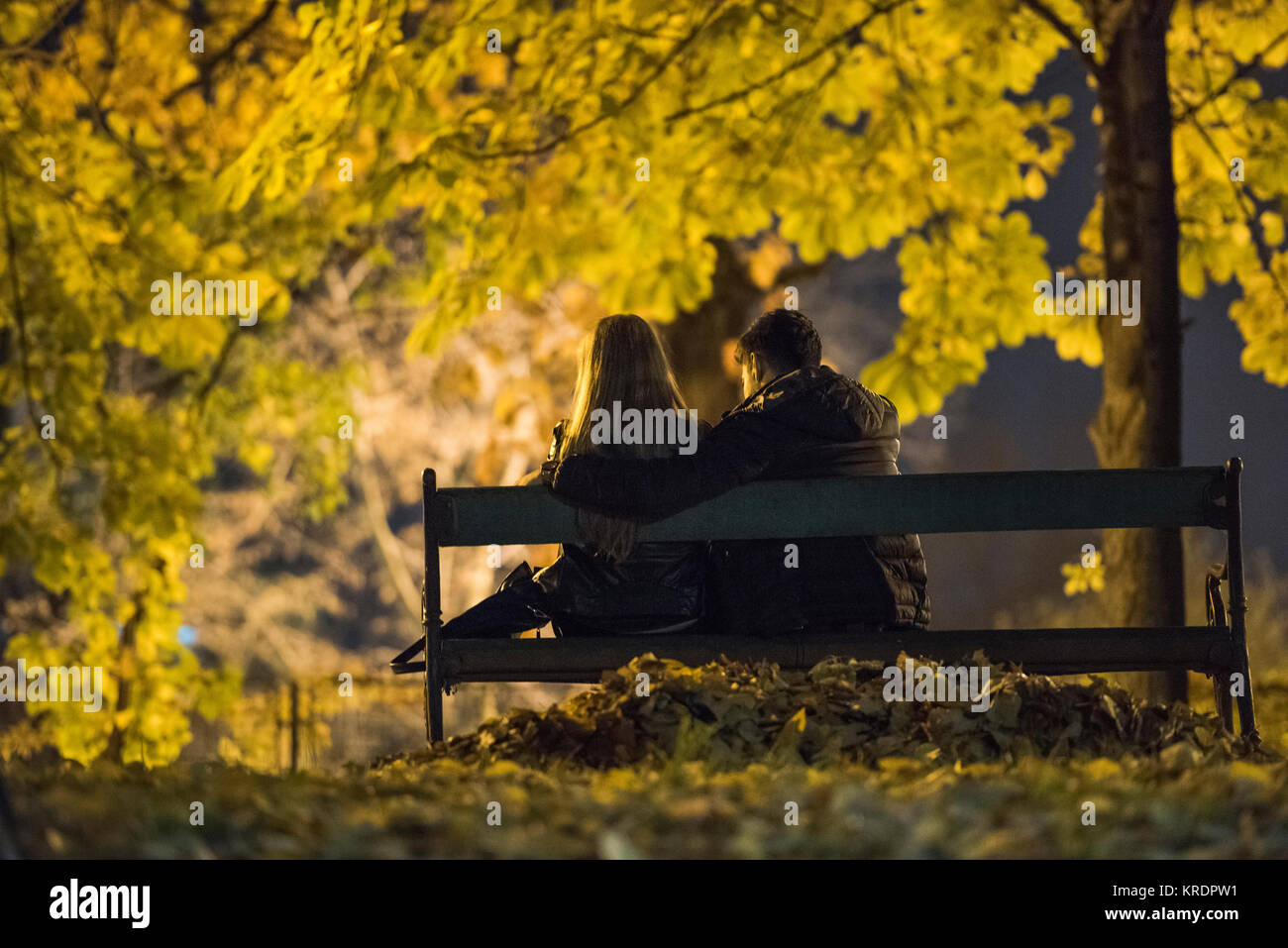 Couple on a bench in an autumn evening Stock Photo - Alamy