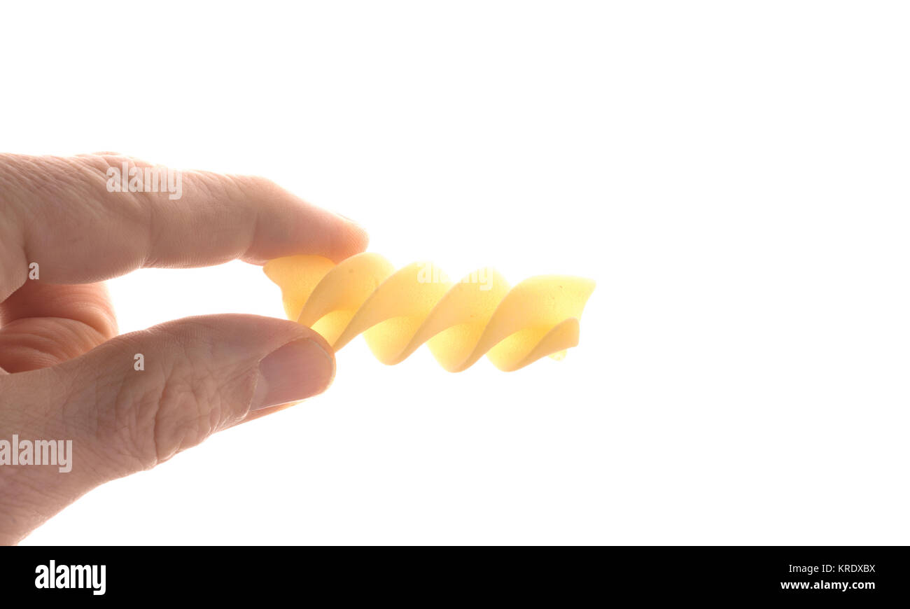 Two fingers hold a spiral noodle (fusilioni), isolated on white Stock ...