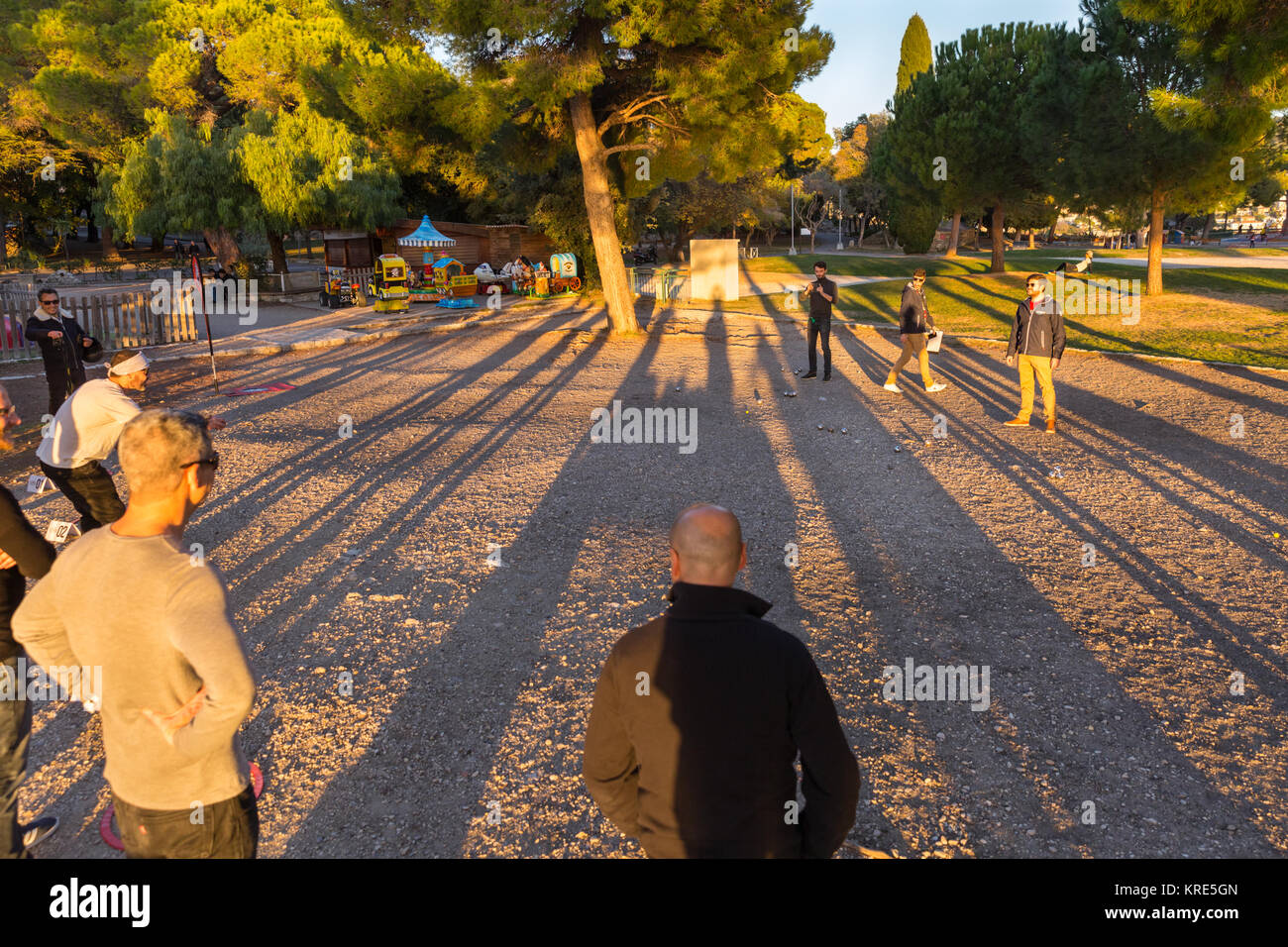 Group of people playing Boules in the evening sun with long shadows ...