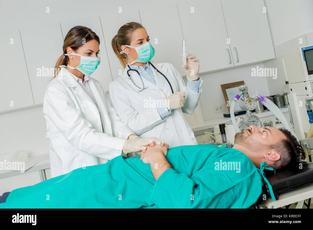 Female doctors preparing male patient for intervention in the hospital ...