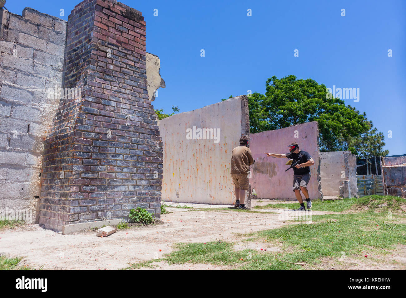 Paintball game arena player gun in old broken house wall with pelet ...