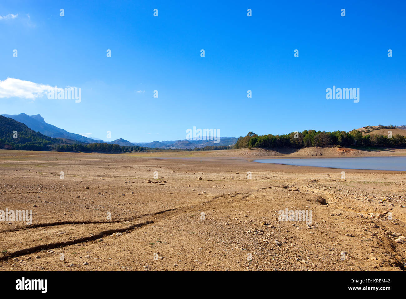 a sandy reservoir bed with some water woodland and mountain scenery ...