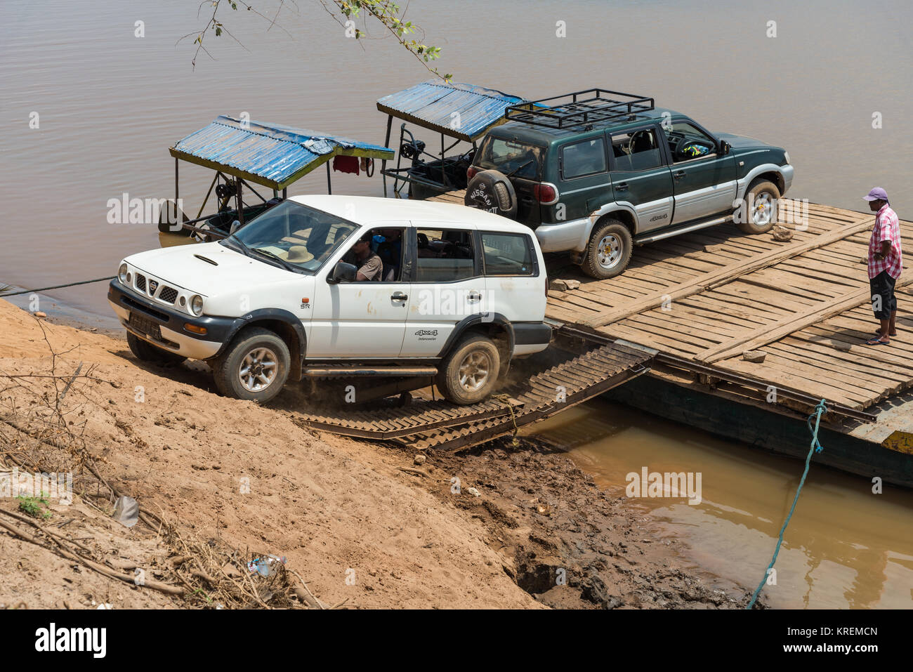 A white SUV driving off ferry boat after crossing Mania River ...