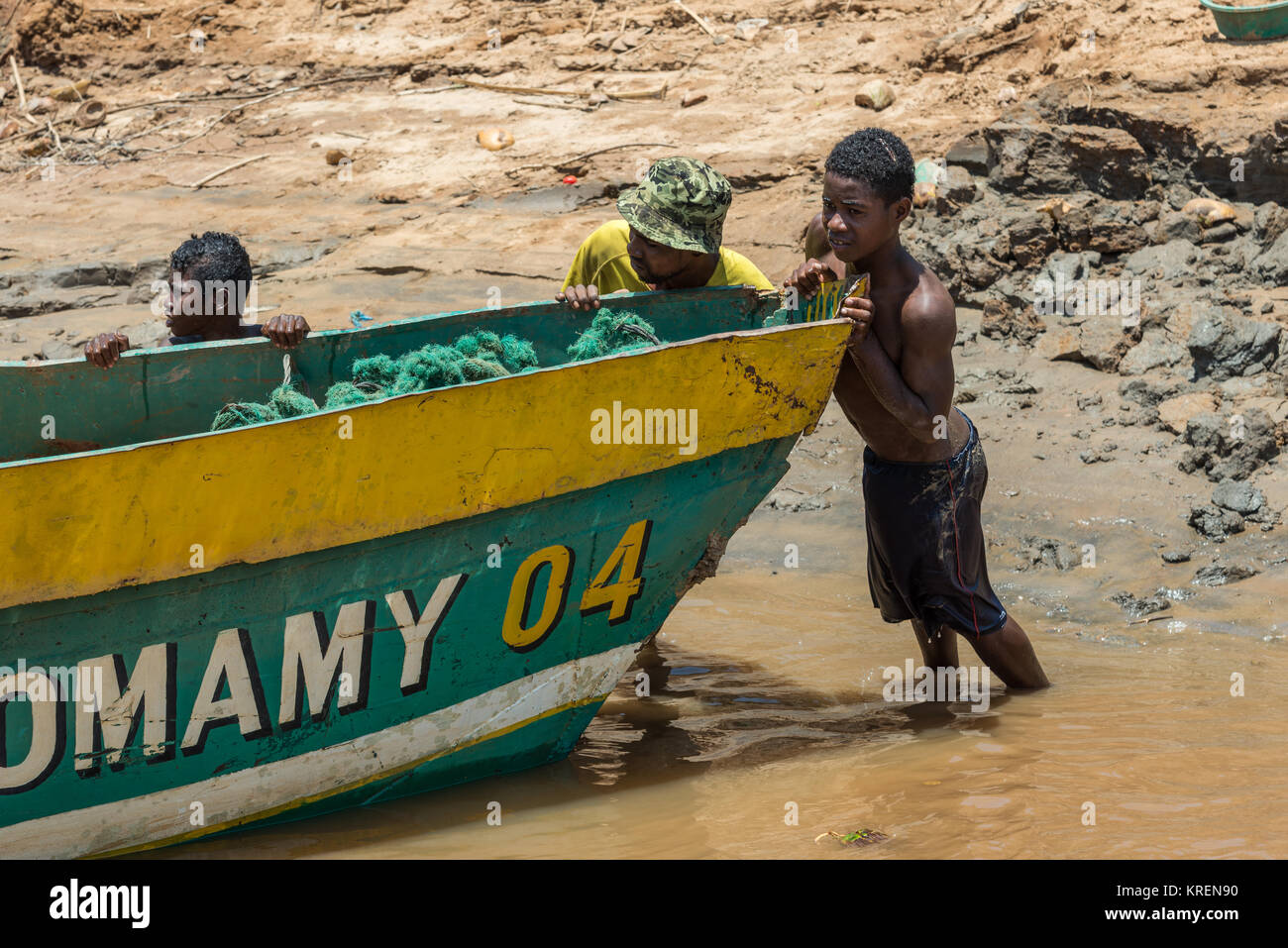 A Malagasy man led two boys pushing the bow of a ferry boat by the ...