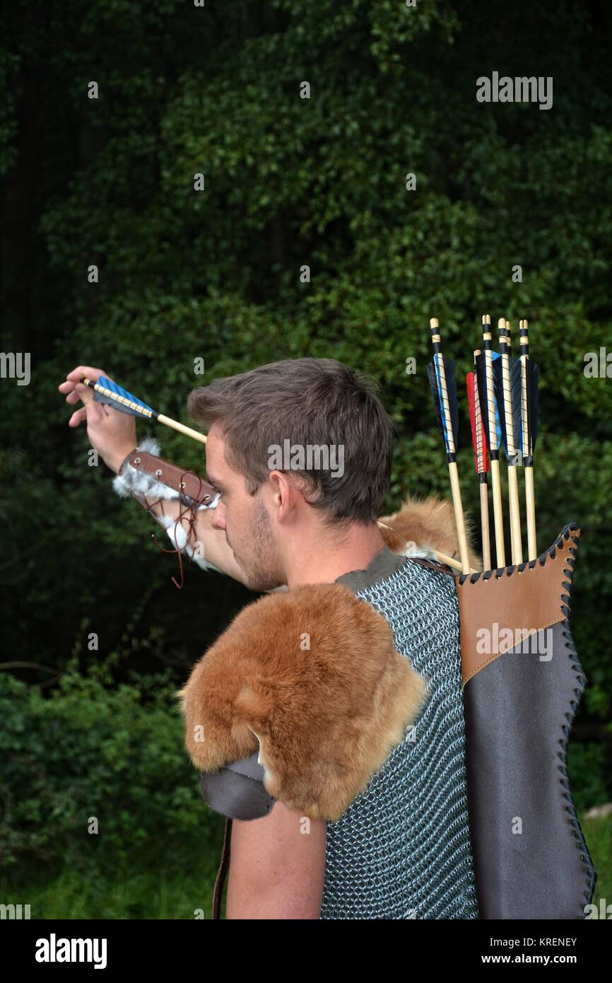 young medieval archer with chain mail reaches for arrow,with bow in ...