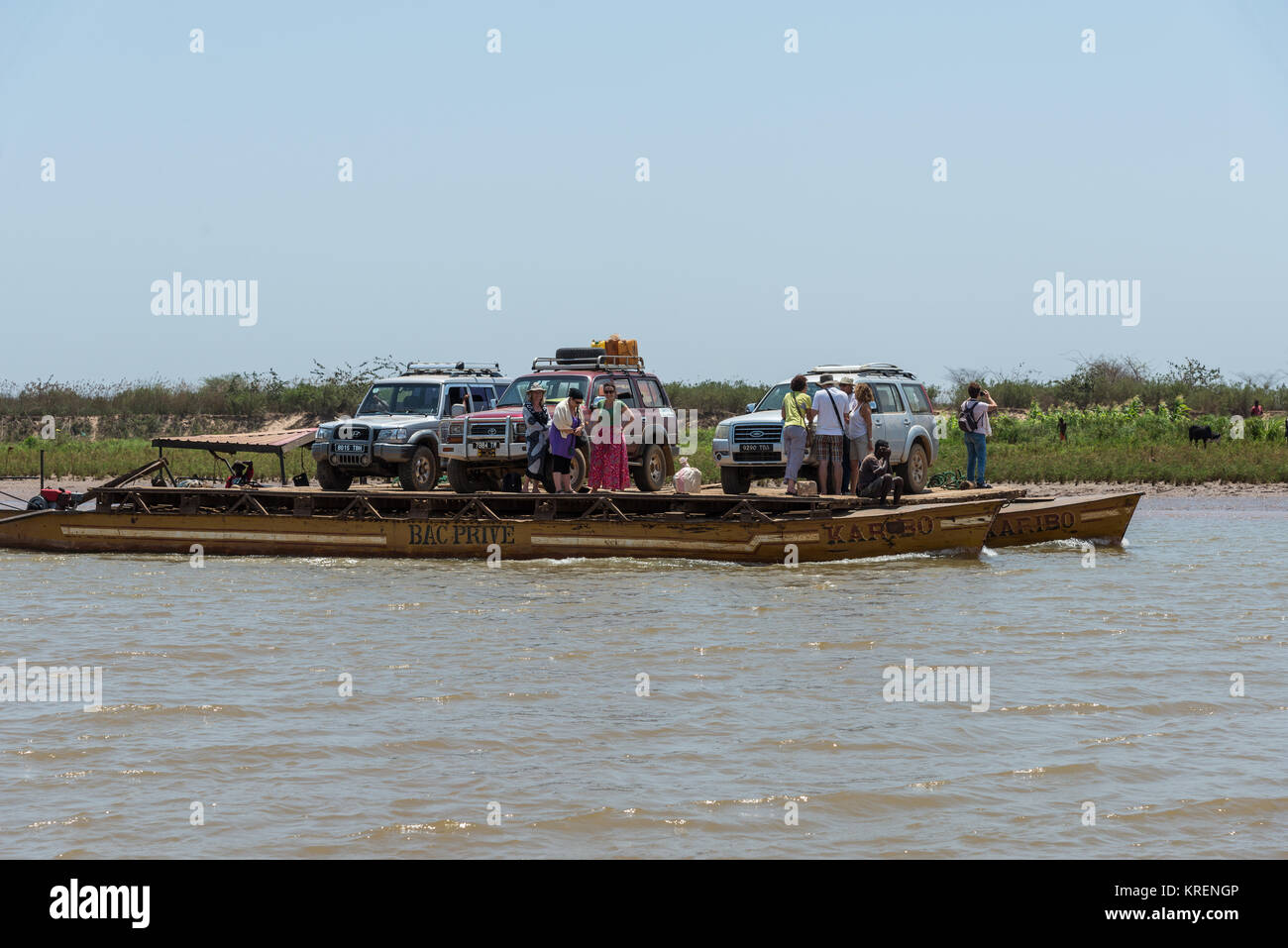 SUVs and passengers on board of a ferry boat on Mania River. Madagascar ...