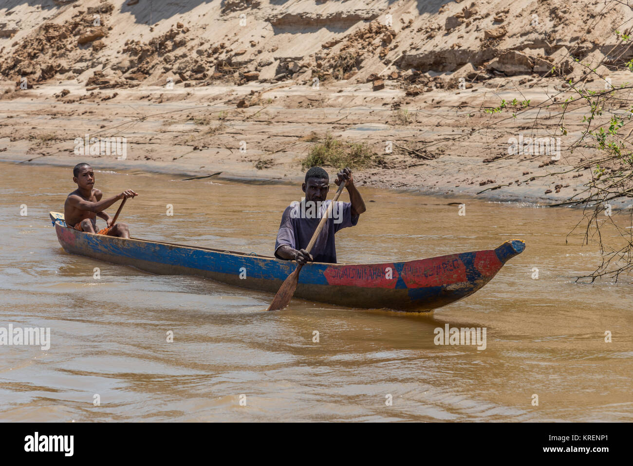 A Malagasy man and a boy paddle their dugout canoe on Mania River ...