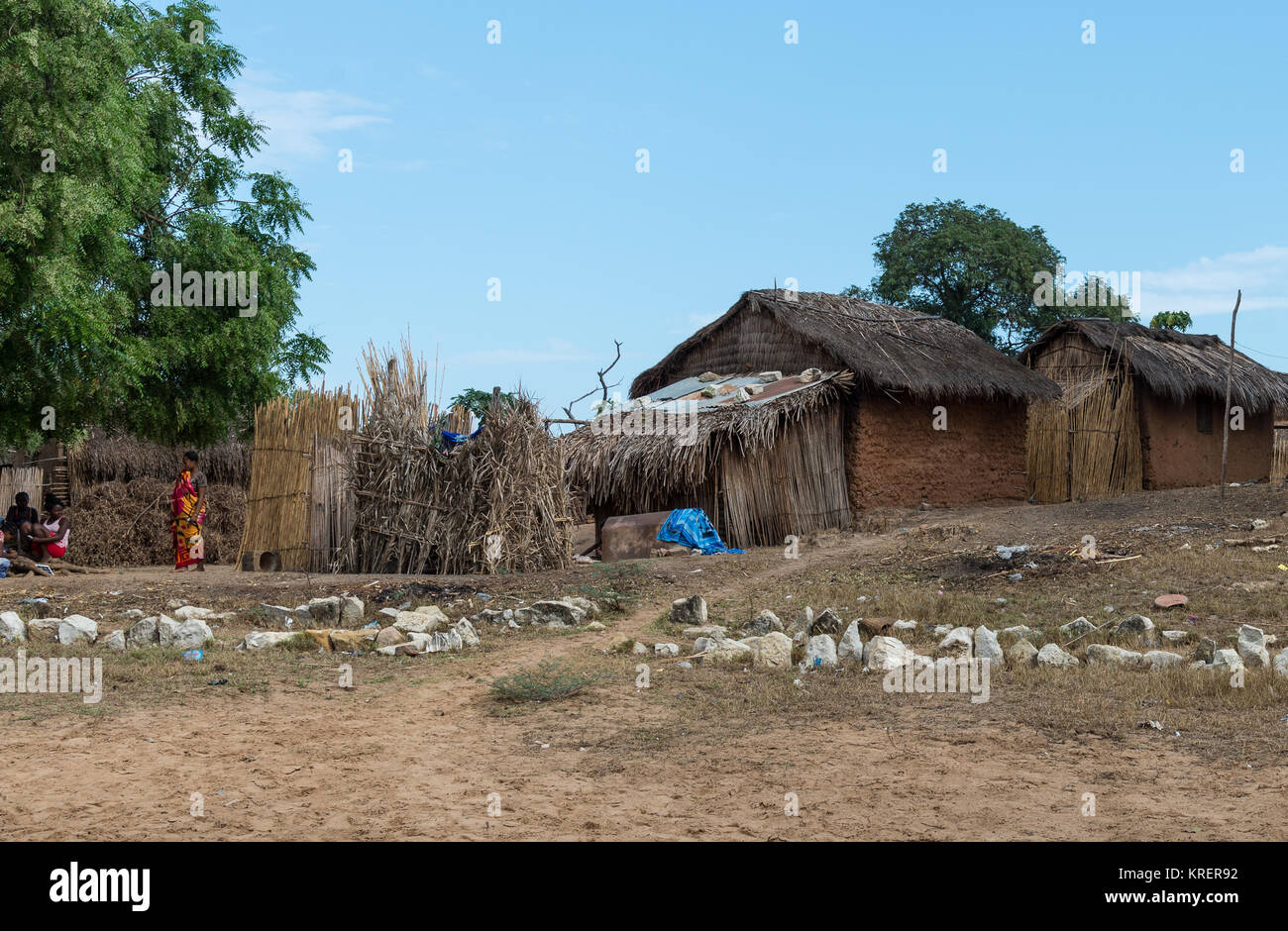 Locals gather in front of their mud wall grass top huts in a Malagasy ...