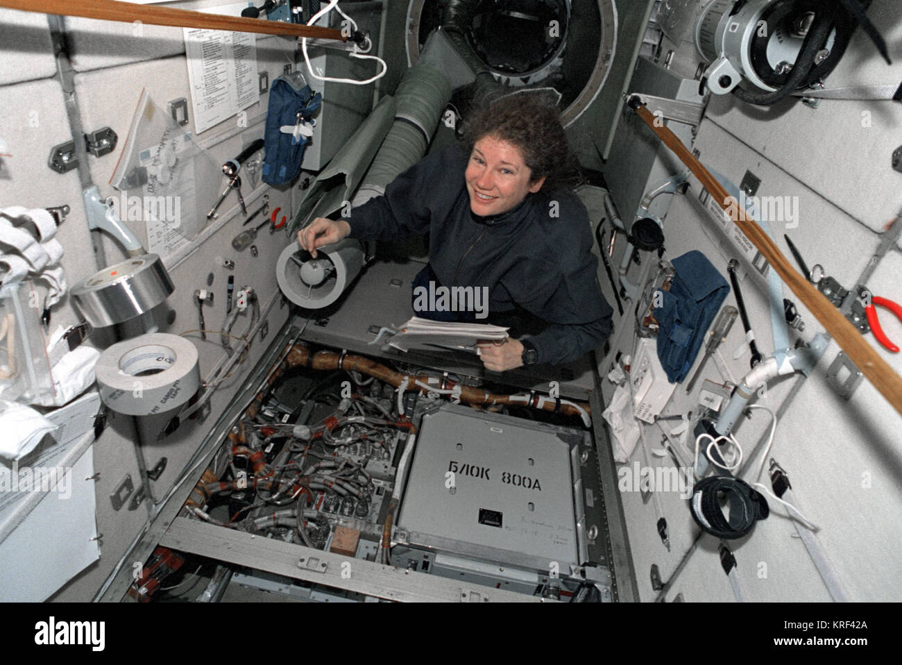 Susan J. Helms performs battery maintenance beneath the floor of the ...