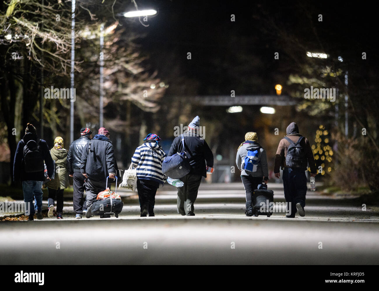 Munich, Germany. 14th Dec, 2017. Homeless people walk towards the night ...