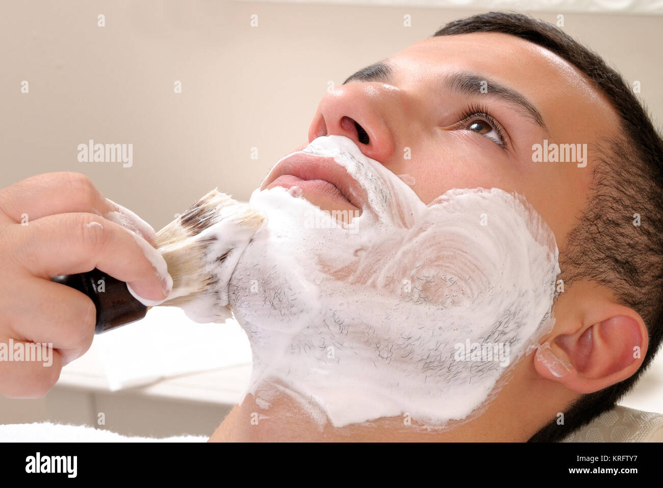 Shaving at the barber of a young boy in retro style with razor and ...