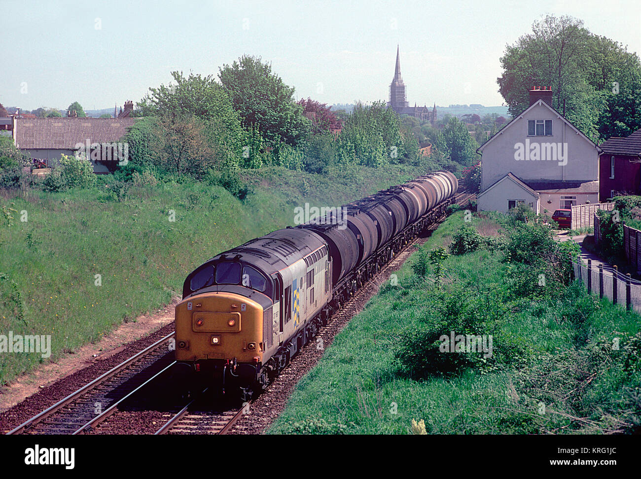 A class 37 diesel locomotive working a train of four wheeled oil tanks ...