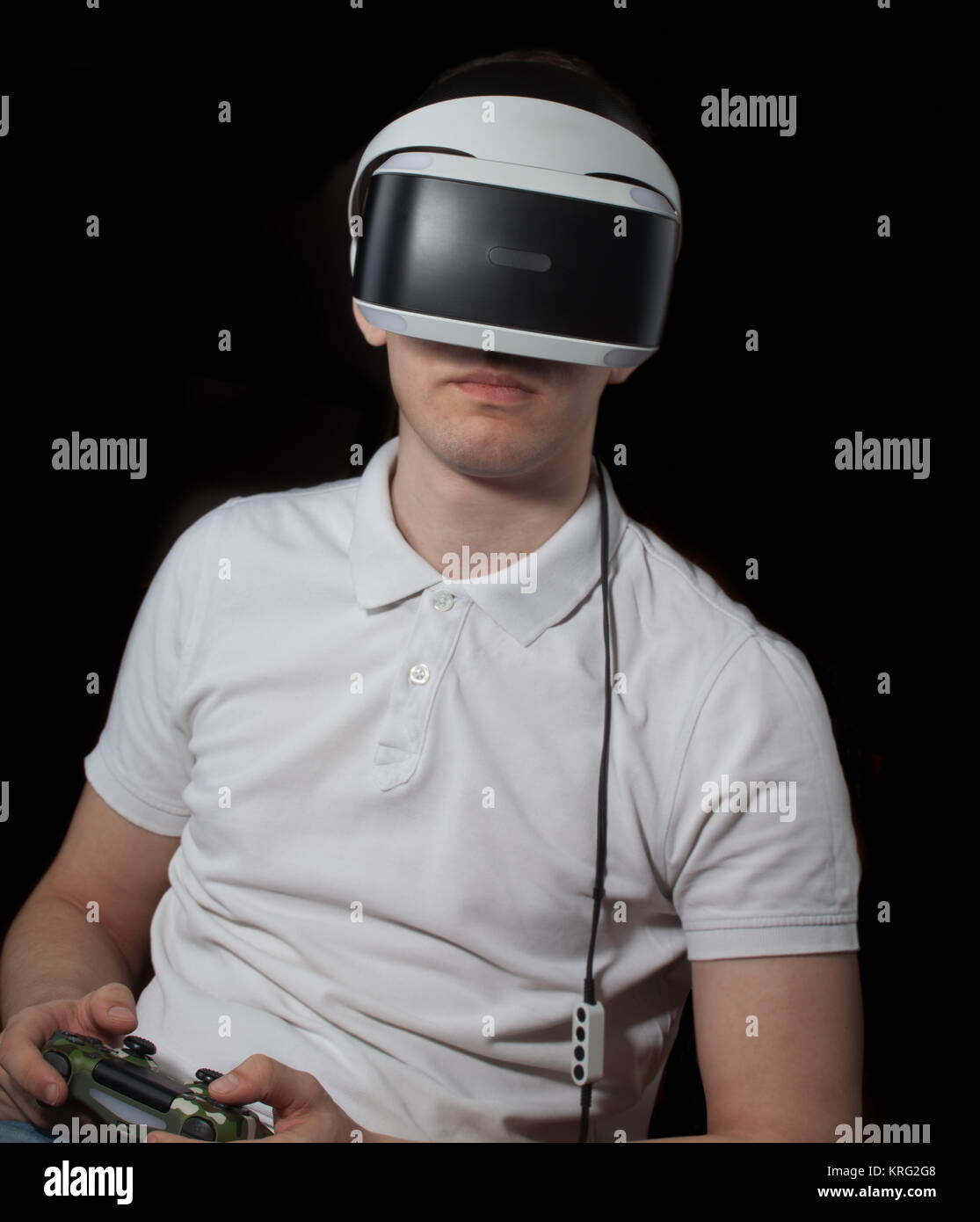 Sitting Young man plays in computer game with VR helmet Stock Photo - Alamy