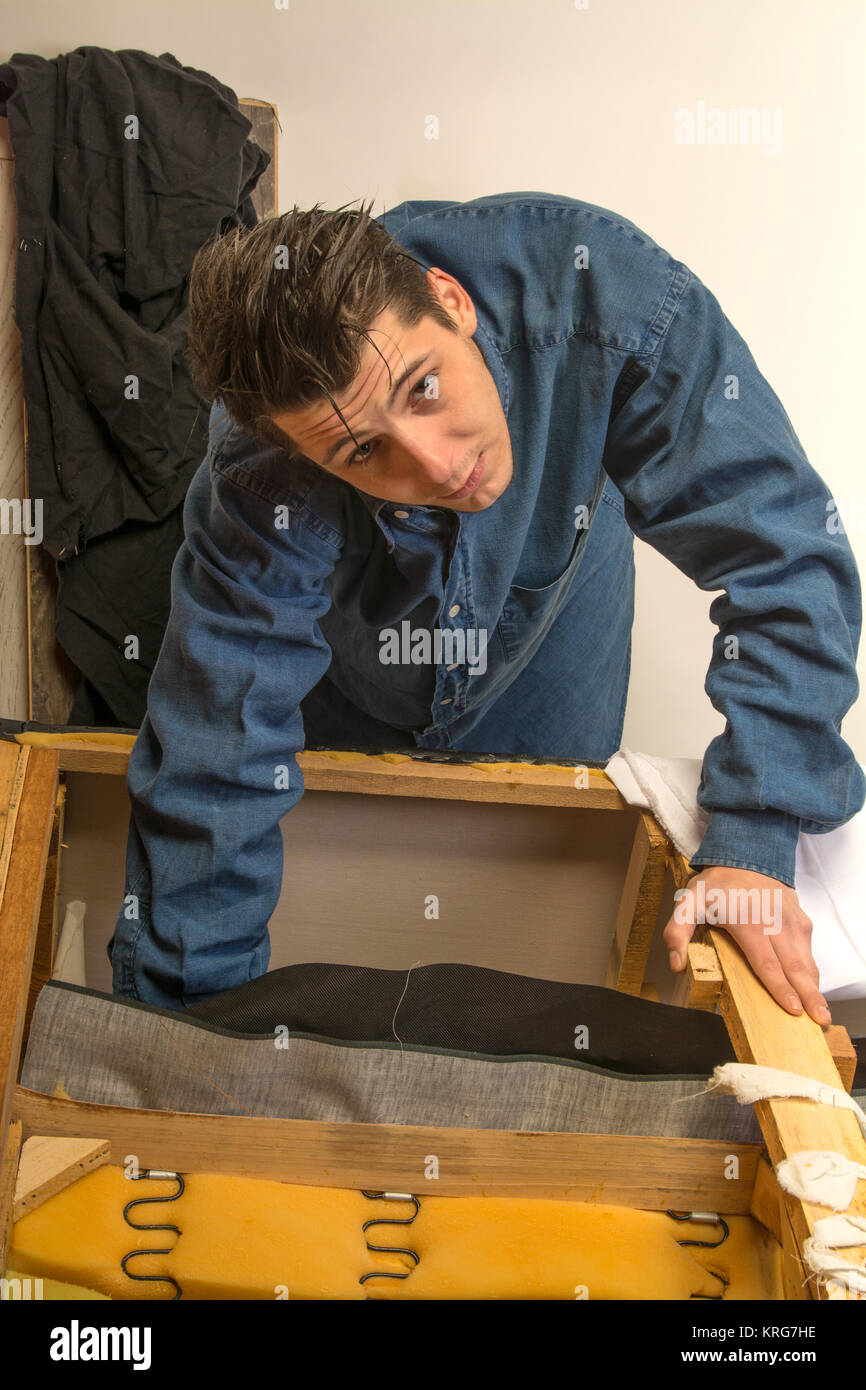 upholsterer padding a sofa with open framing in the upholsterer shop ...