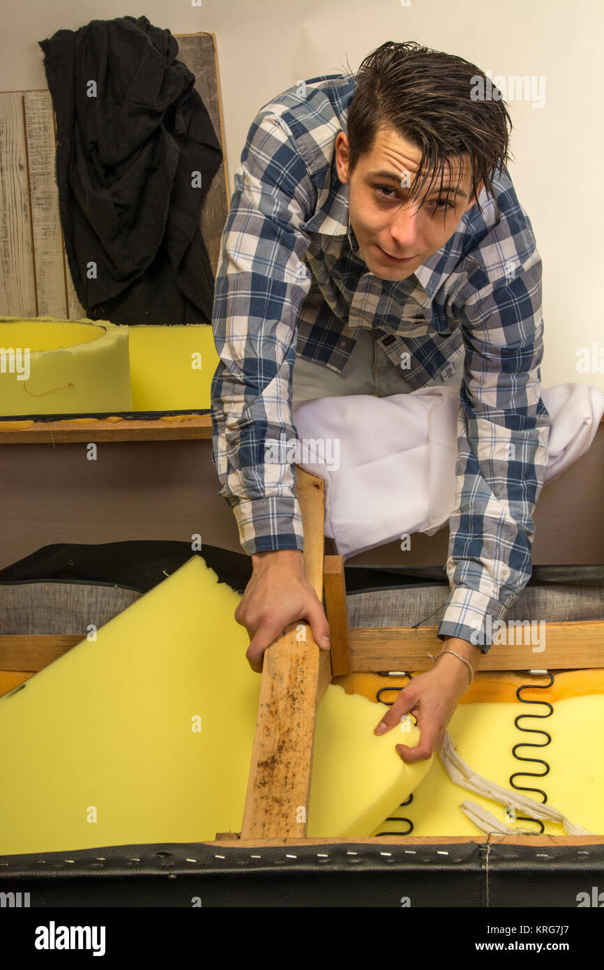 upholsterer padding a sofa with open framing in the upholsterer shop ...