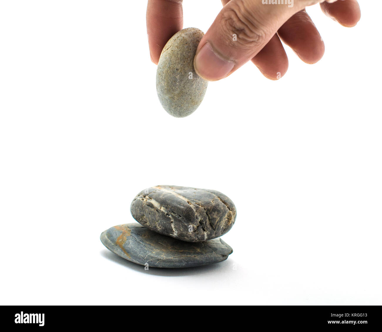 The stones are stacked and the hands are holding stones being laid on a ...