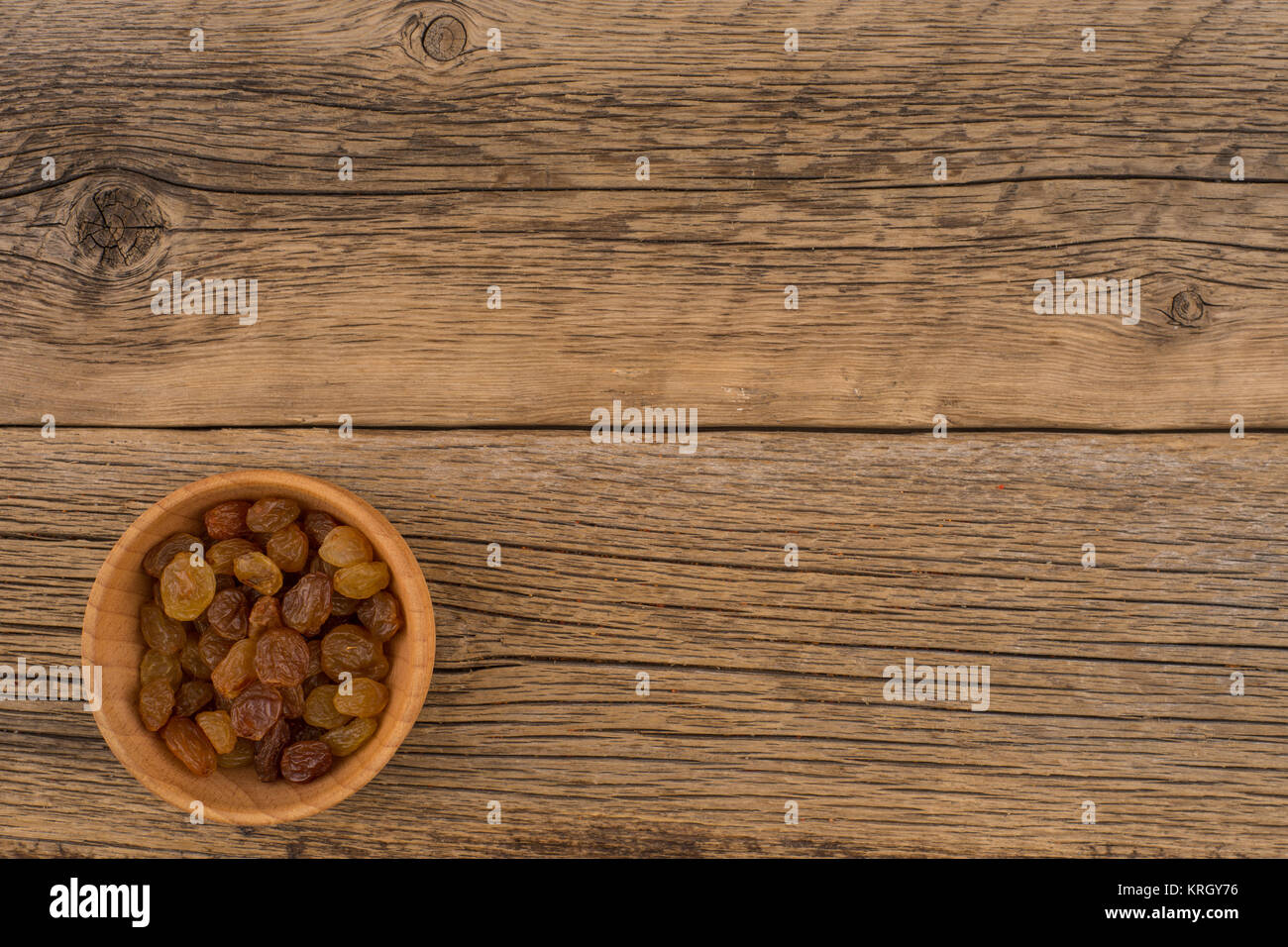 Raisins in a wooden bowl on the old wooden table Stock Photo - Alamy