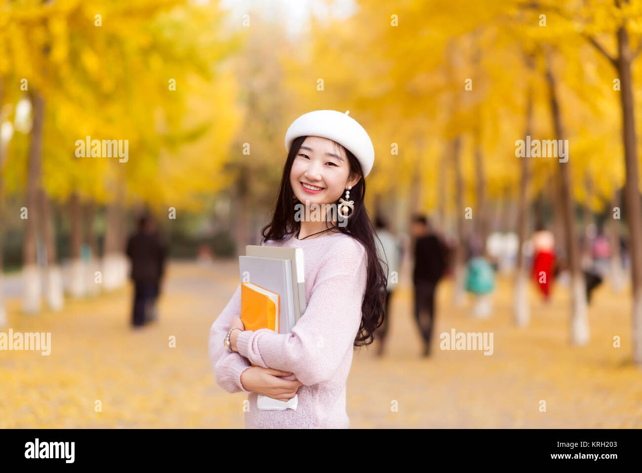 Portrait of a smiling pretty woman reading a book on an autumns day ...