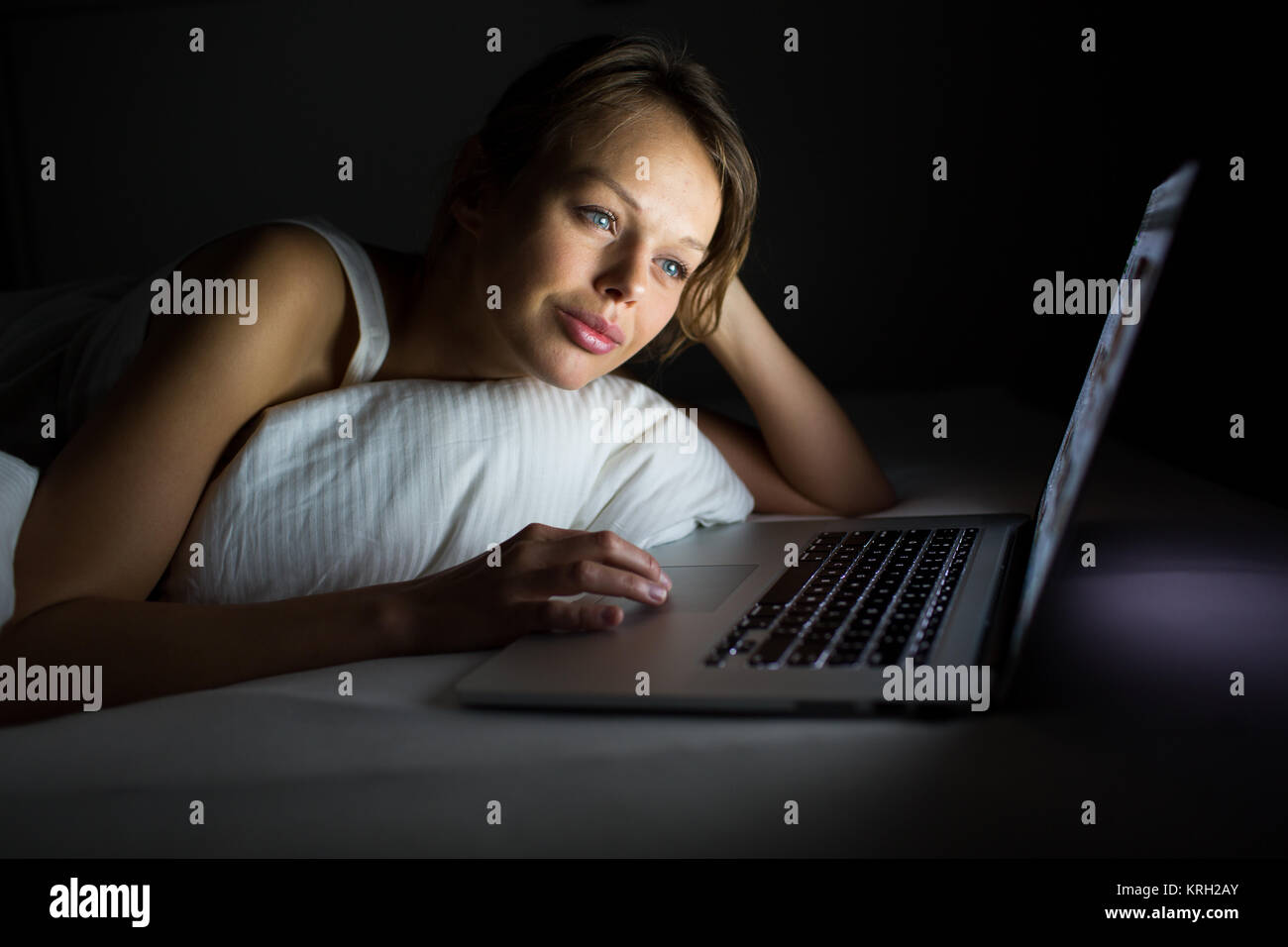 Pretty, young woman using her laptop computer in bed Stock Photo - Alamy