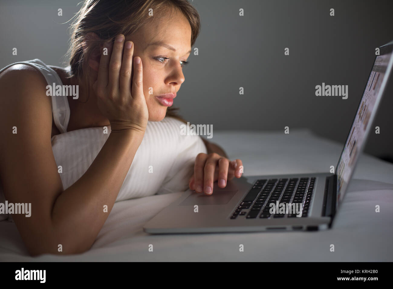 Pretty, young woman using her laptop computer in bed Stock Photo - Alamy