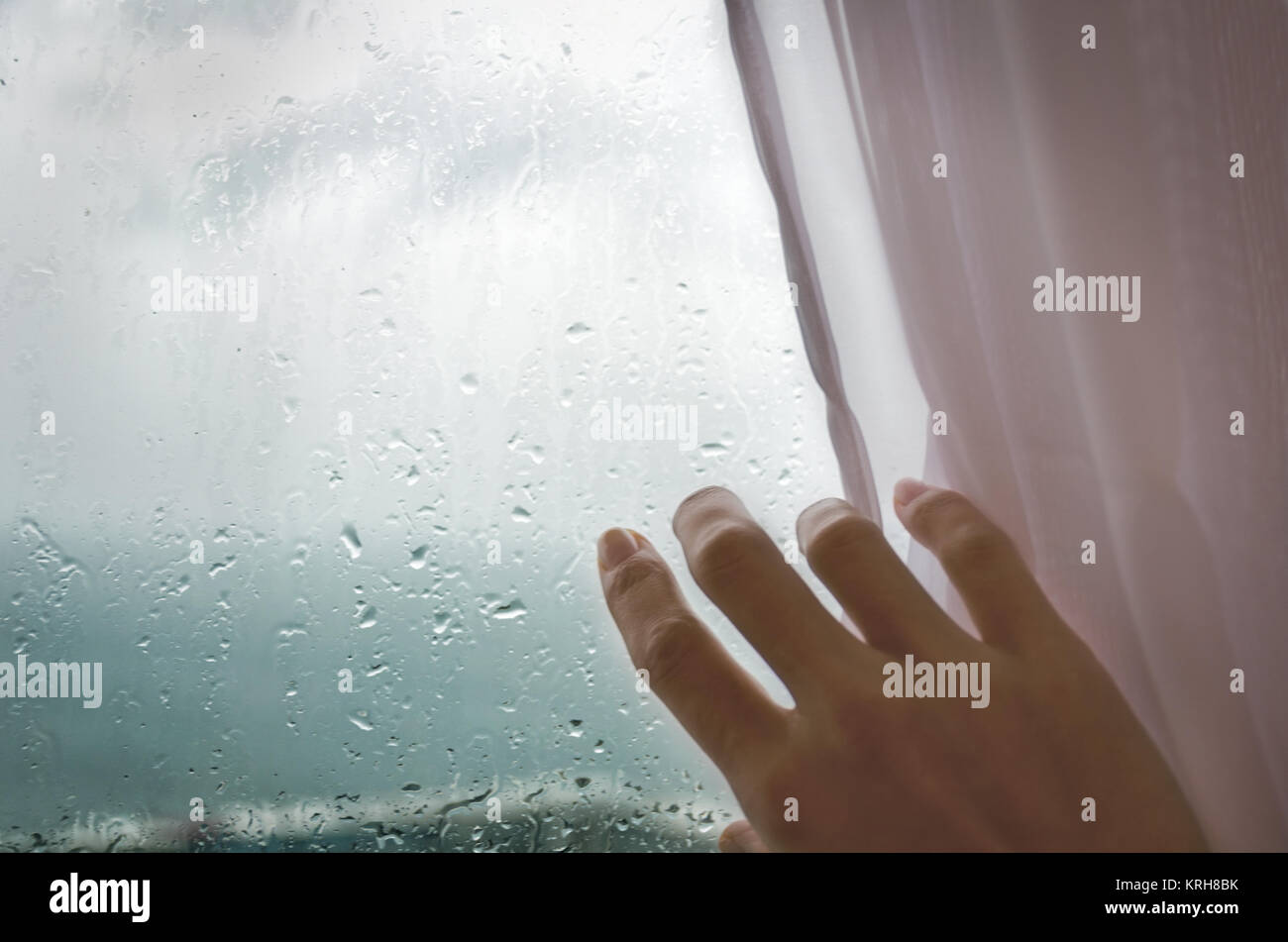 Rainy weather - a woman's hand pulls the blind from the rainy window ...