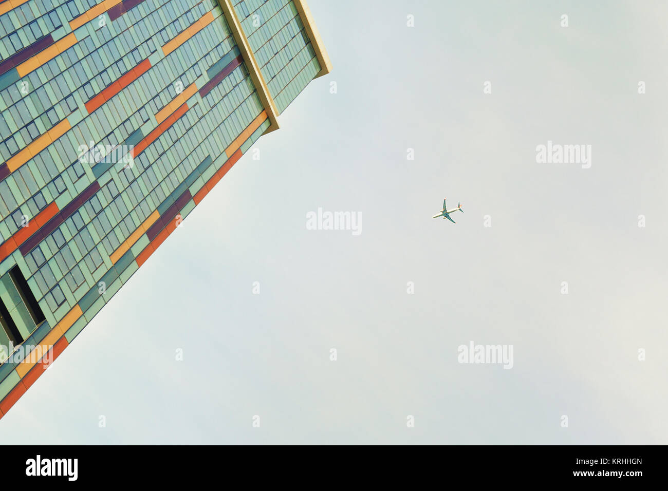 Plane flies on the background of a skyscraper with colorful windows ...