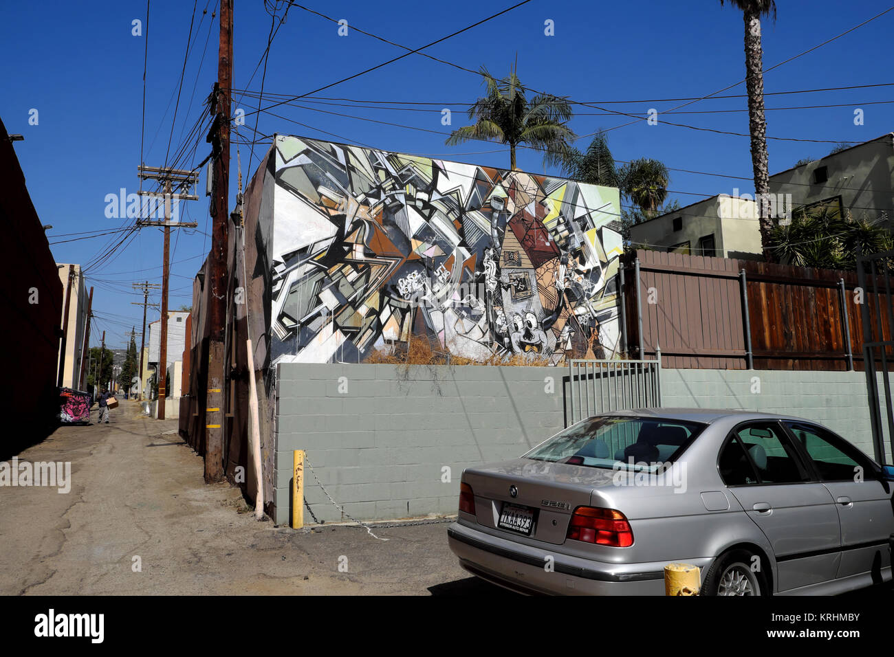 An abstract mural on a wall and parked car in a back alley in the Los ...