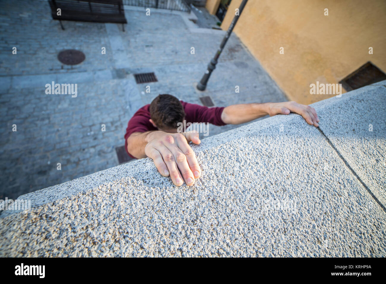 Young man hanging on wall on hands and trying to climb up while doing ...