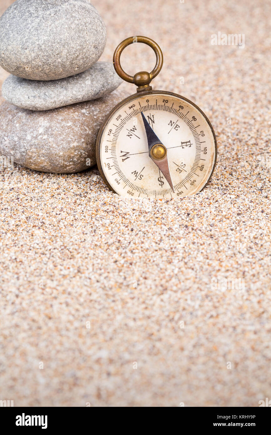 Vintage compass with three pebble stones portrait view Stock Photo - Alamy