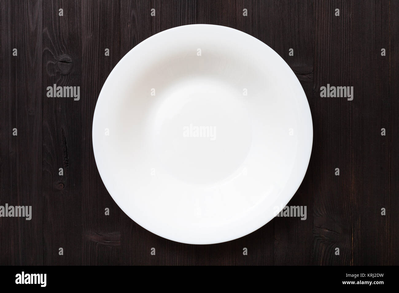 top view of white deep plate on dark brown table Stock Photo - Alamy